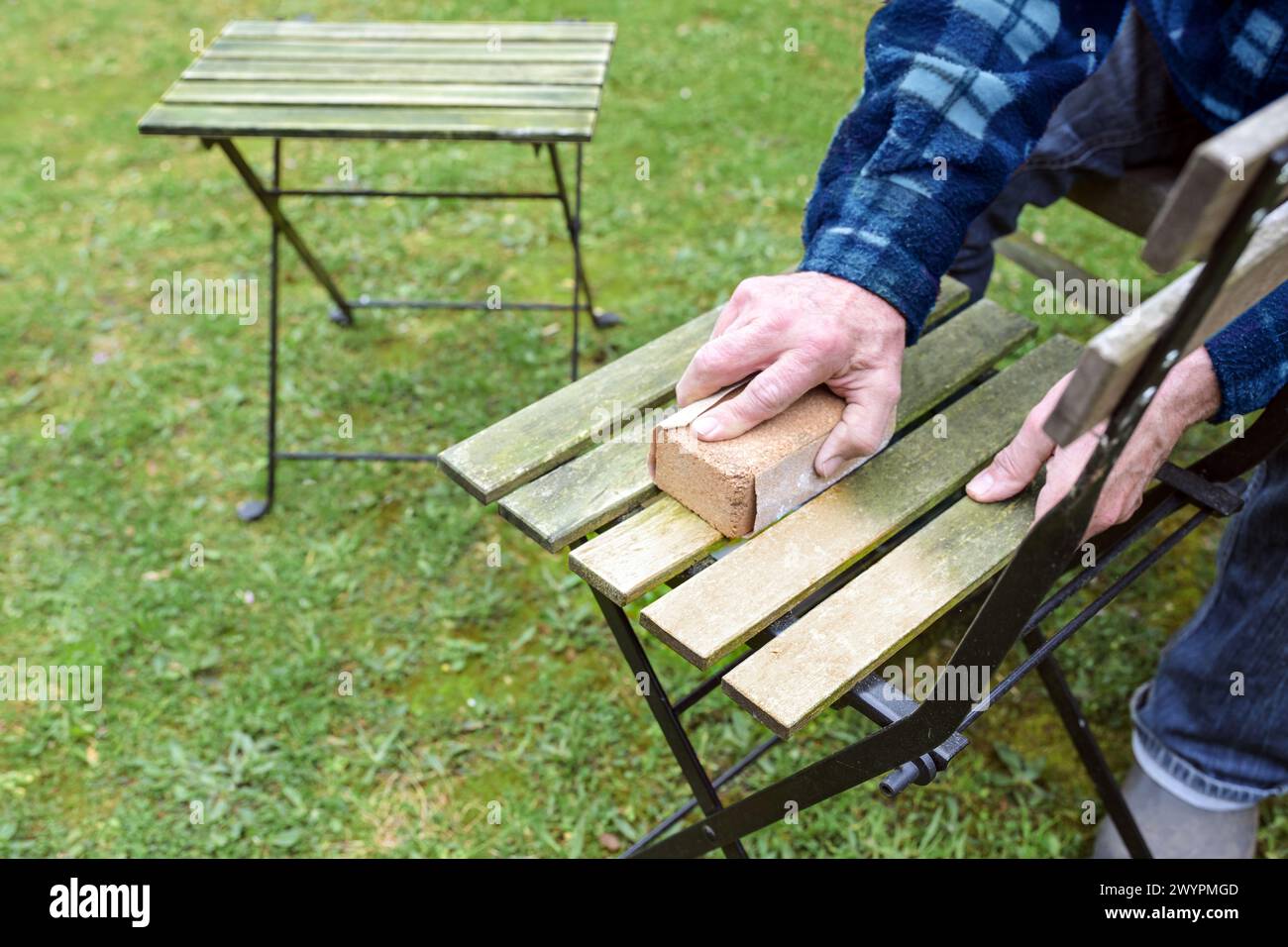 Man is cleaning and restoring wooden outdoor furniture, sanding the ...