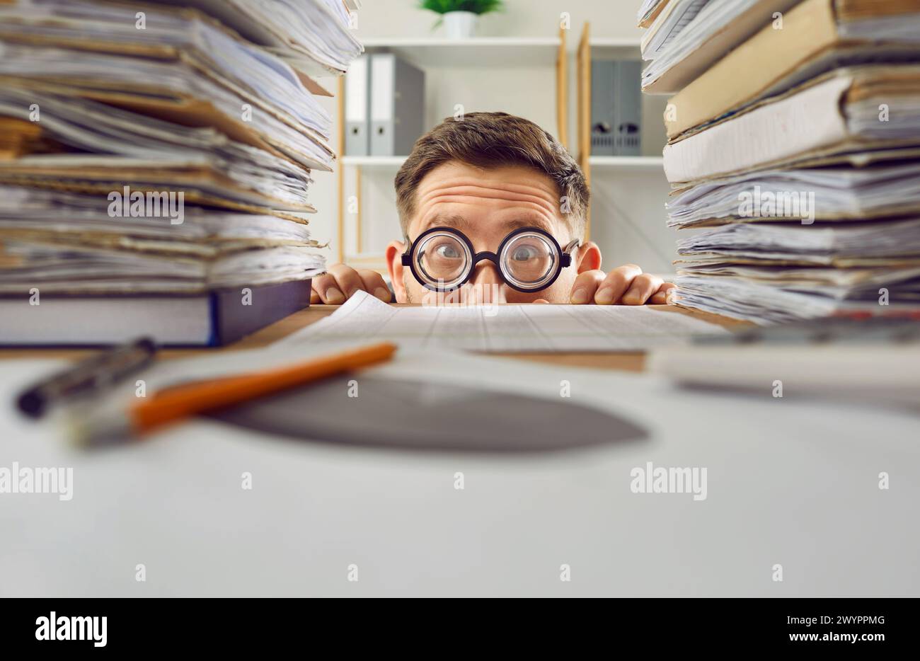 Funny worker employee hiding under desk at workplace in office with a ...
