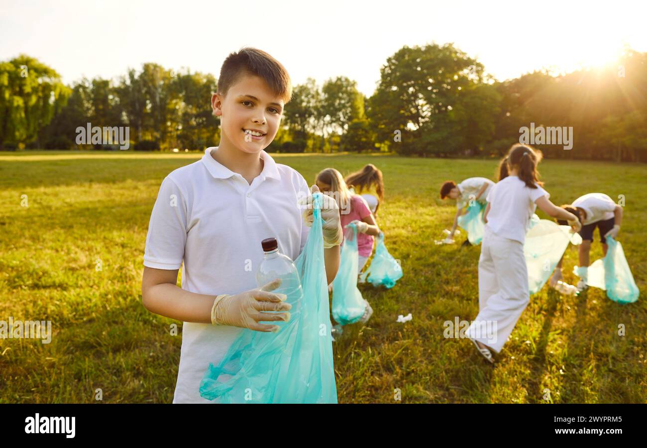Teenage smiling boy with trash bag collecting plastic garbage in the ...
