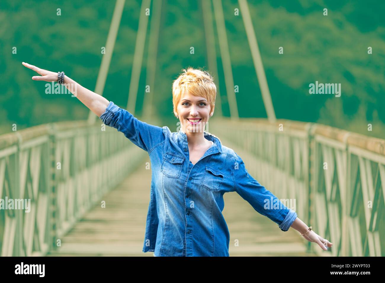 Joy radiates from the woman in denim, arms wide open on a bridge above ...