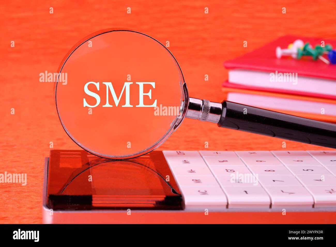 SME (or small and medium enterprises) symbol through a magnifying glass ...