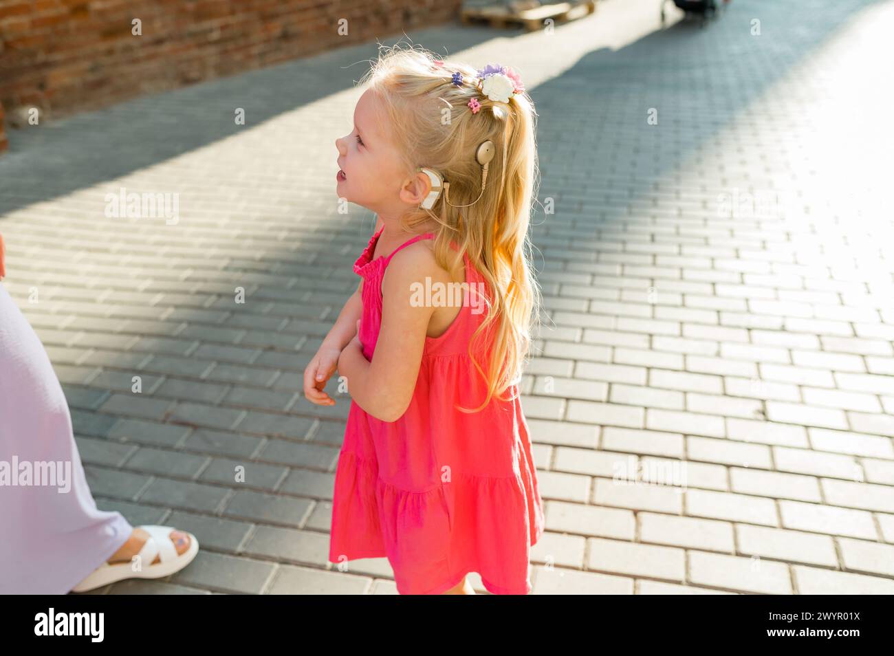 Child girl with hearing aid cochlear implant in pink dress having fun ...