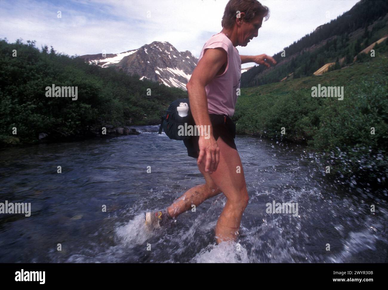 A runner crosses a stream in the hardrock 100. Billed as the toughest ...