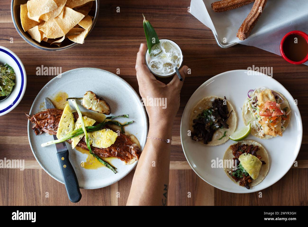 Hand setting drink on table full of food dishes Stock Photo - Alamy