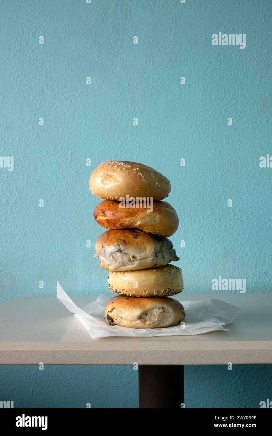 Stack of bagels on a table against a light blue wall vertical Stock ...