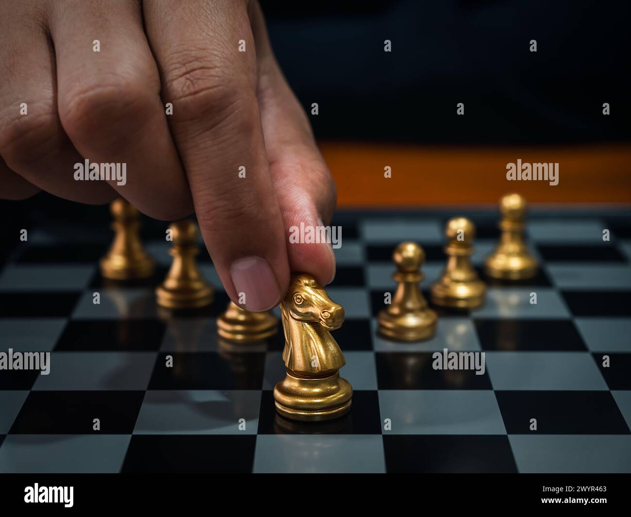 Golden horse, knight chess piece put by player's hand with gold pawn ...