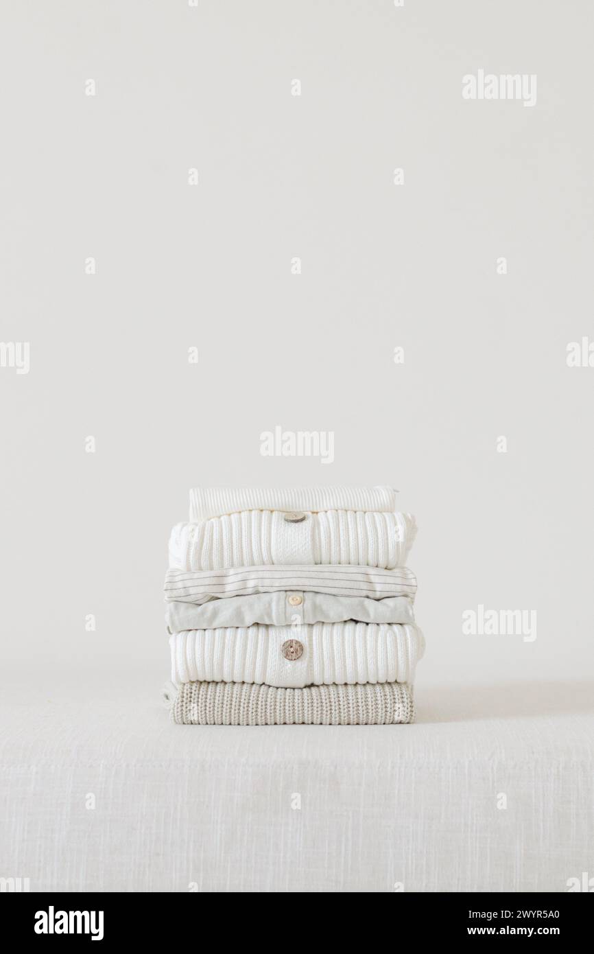 stack of sweaters folded on a linen bench Stock Photo - Alamy