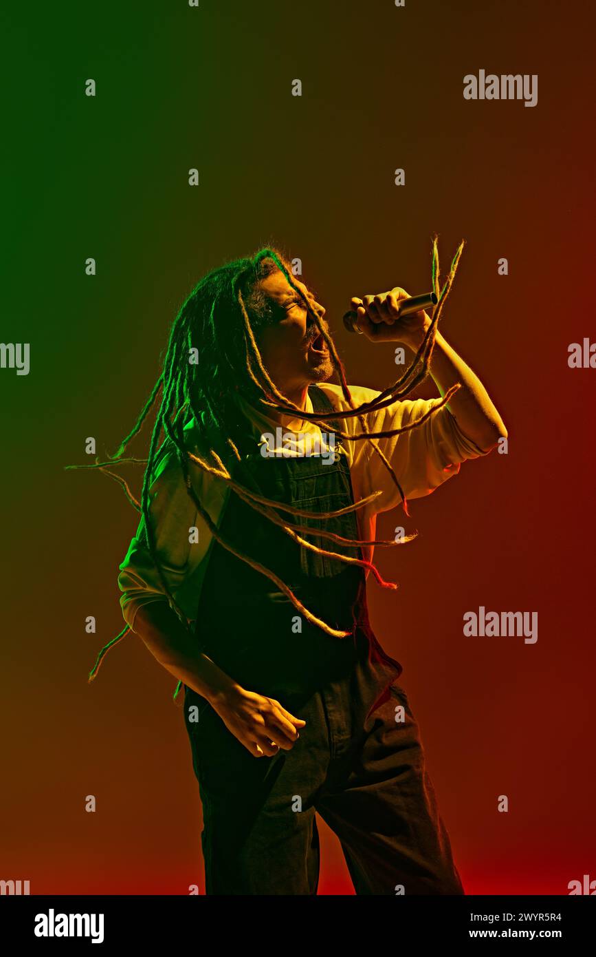Young man, passionate musician with dreadlocks emotionally singing ...