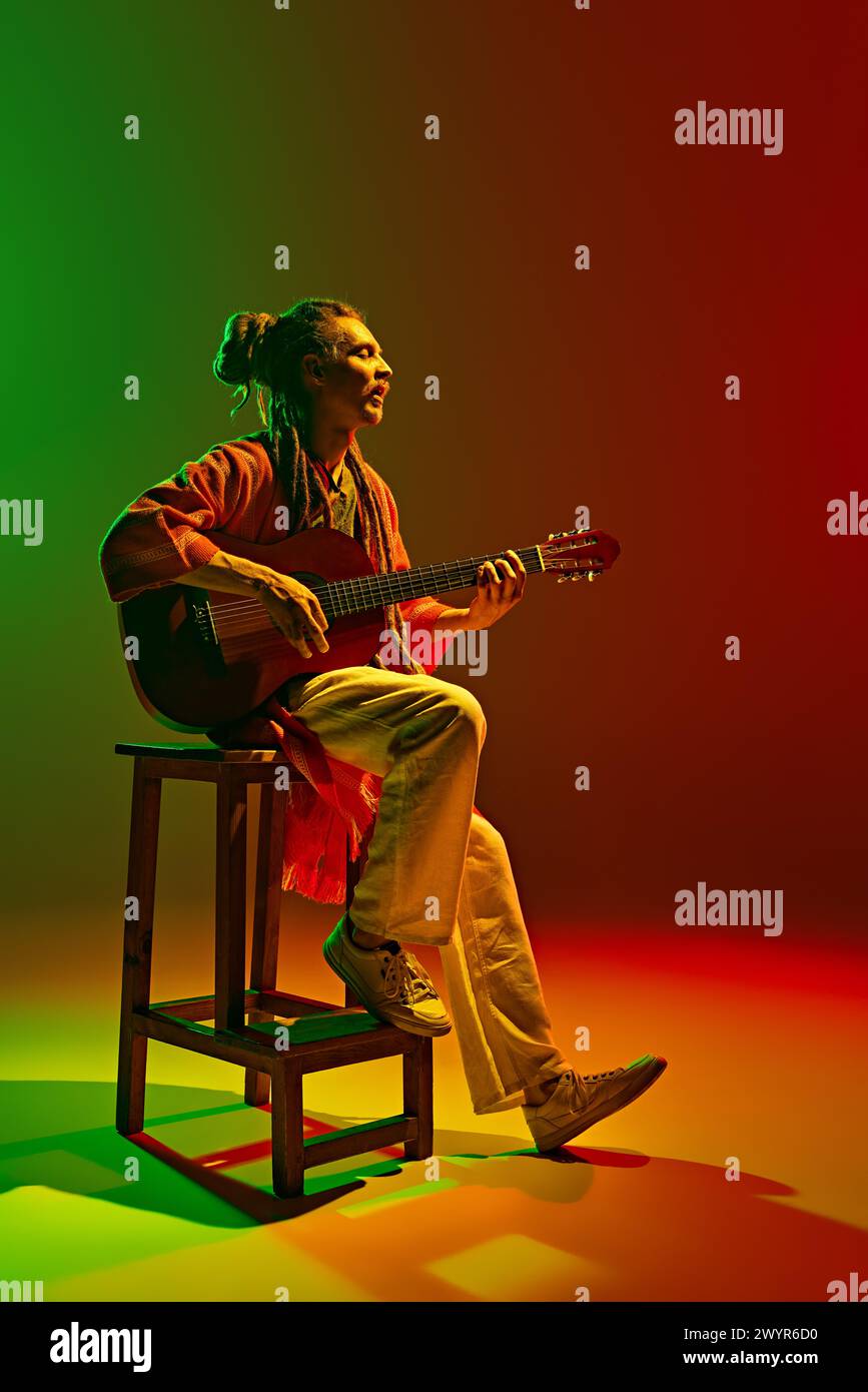 Talented young man, musician with dreadlock sitting on chair and ...
