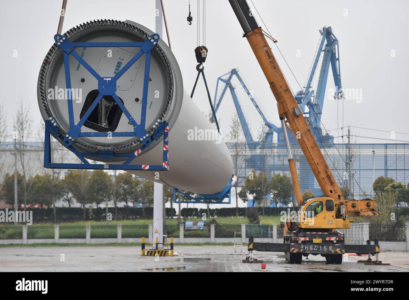 YANGZHOU, CHINA - APRIL 8, 2024 - A crane lifts wind turbine blades to ...