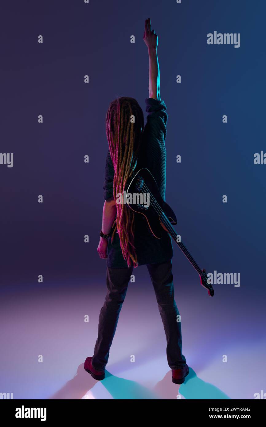 Energetic musician with long dreadlocks performing solo on stage ...