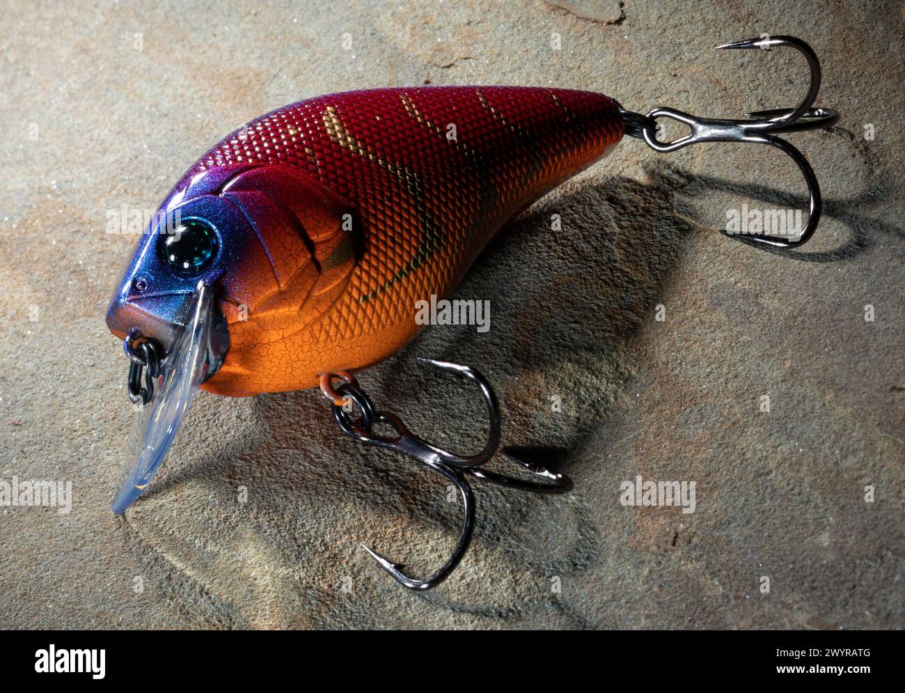 Dark fishing lure thas tis orange in color on a rock Stock Photo - Alamy