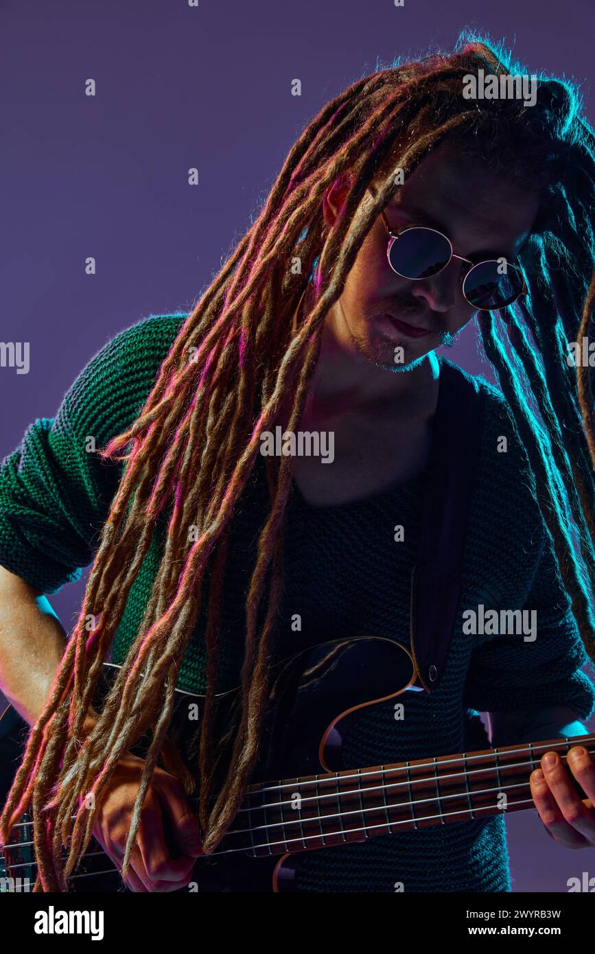 Portrait of stylish guy with dreadlocks, musician playing guitar ...