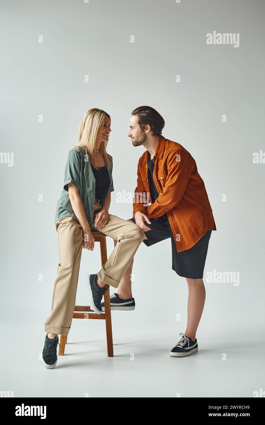 A stylish couple sitting intimately on a stool, exuding romance and ...