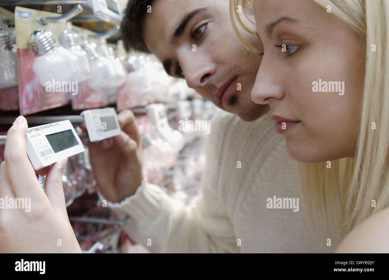 Couple looking at electronic price displays at Eroski shopping center ...