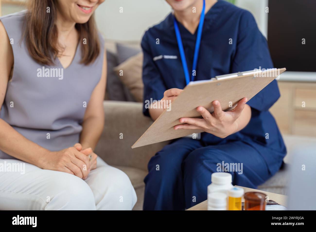 healthcare worker filling in a form with a senior woman during a home ...