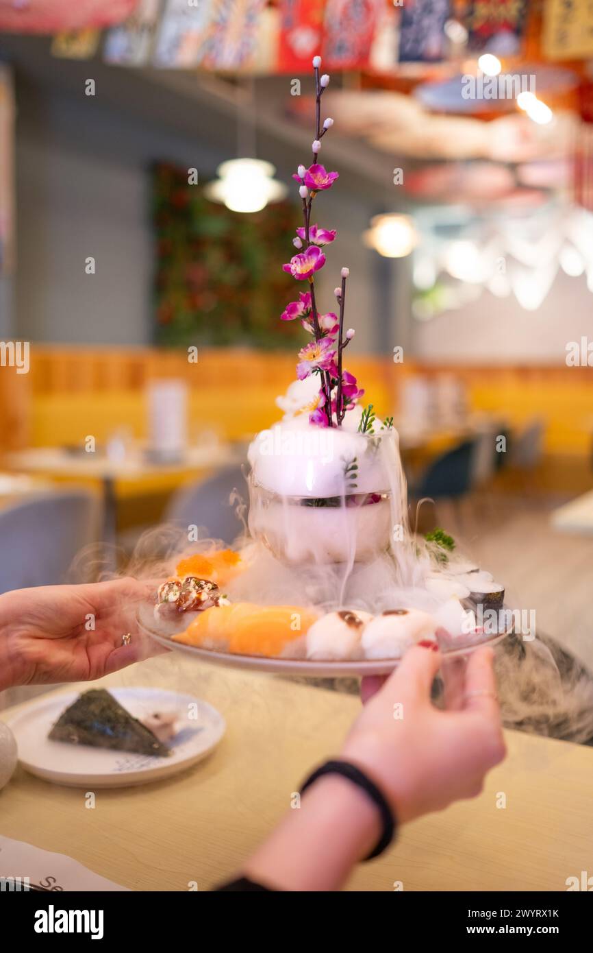 A hand holds a very exotic plate with various types of sushi and ...