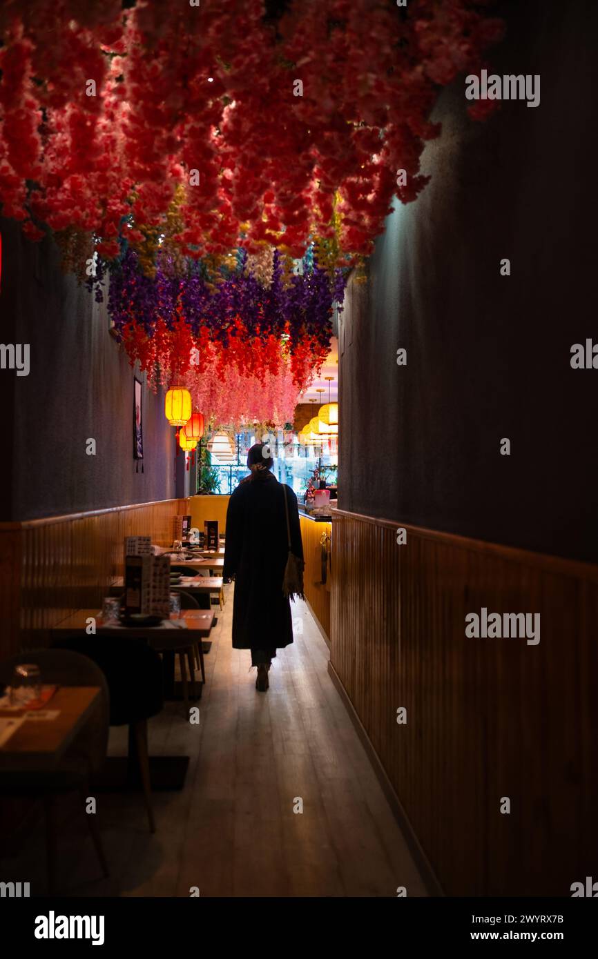 A young woman seen from behind is leaving a Japanese Asian restaurant ...