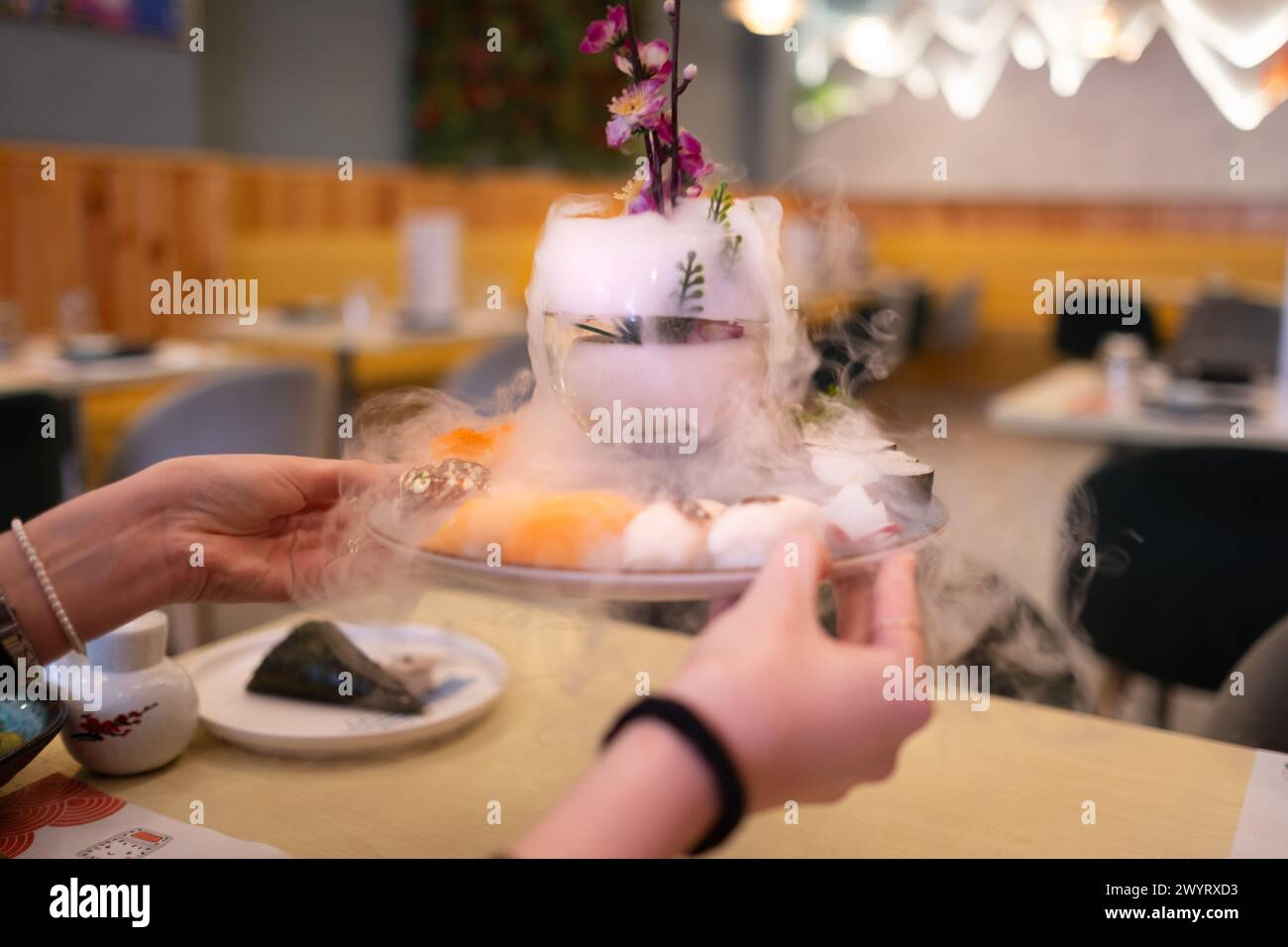 A hand holds a very exotic plate with various types of sushi and ...