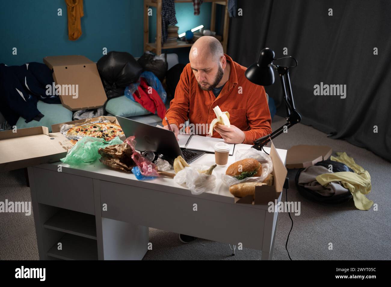 Adult serious male student working studying in messy room Stock Photo ...