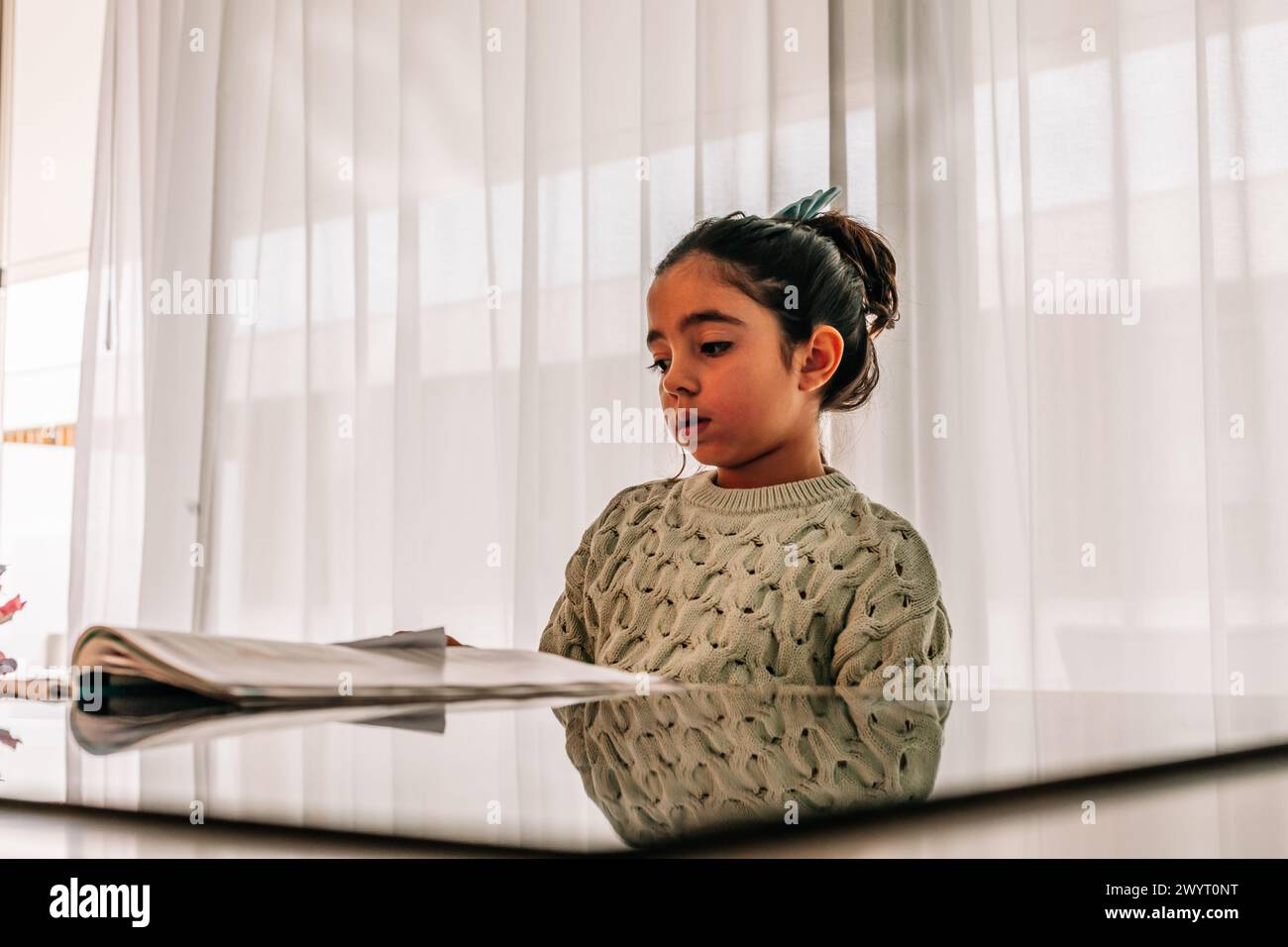 Girl doing school homework, reading book at home Stock Photo - Alamy