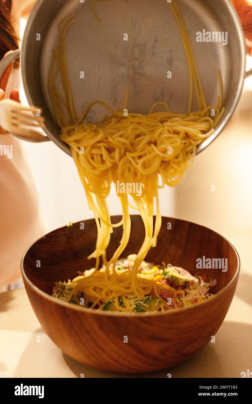 Pouring pasta into a salad ready to eat Stock Photo - Alamy