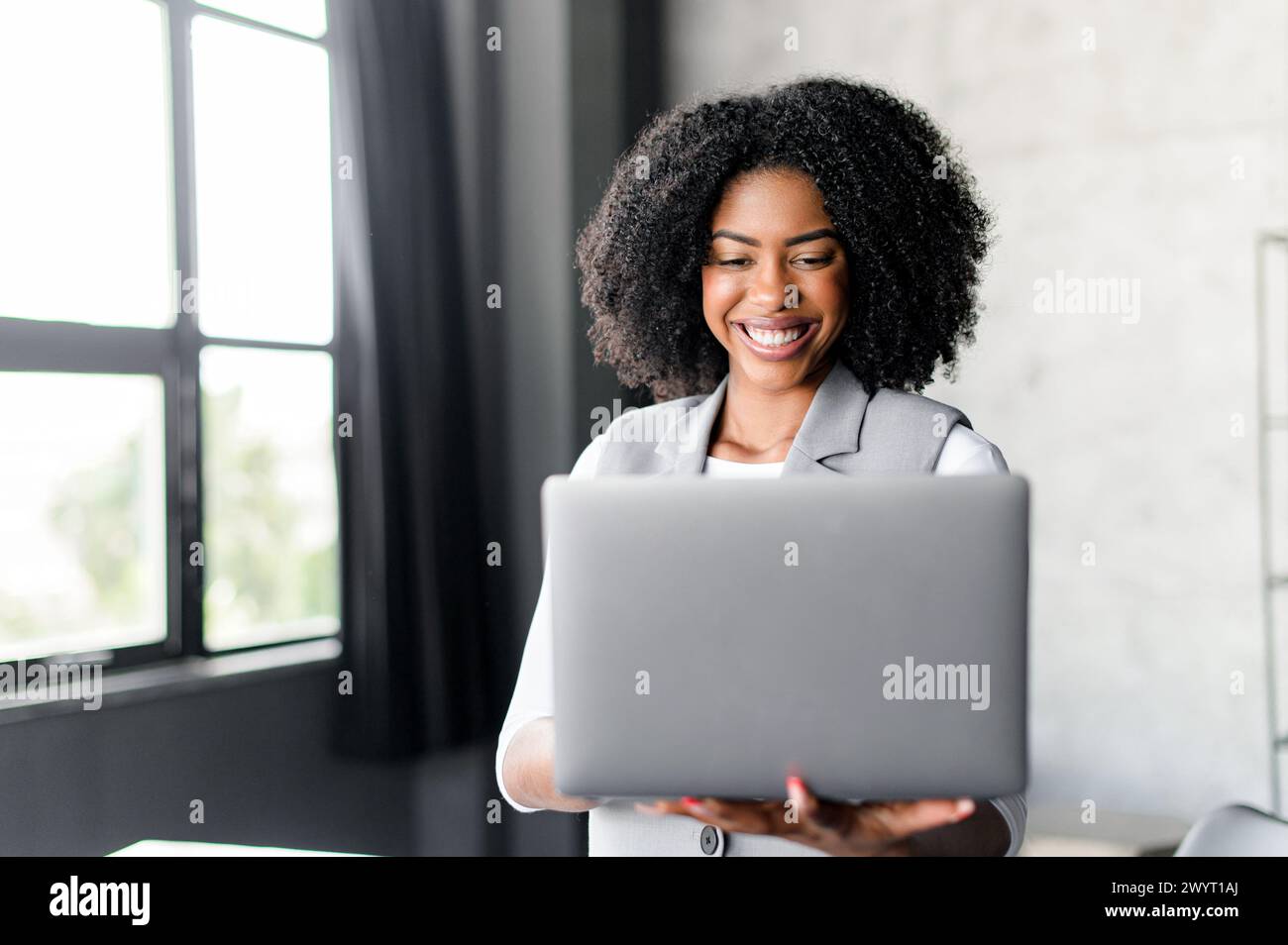 A charismatic African-American businesswoman holds her laptop, her face ...