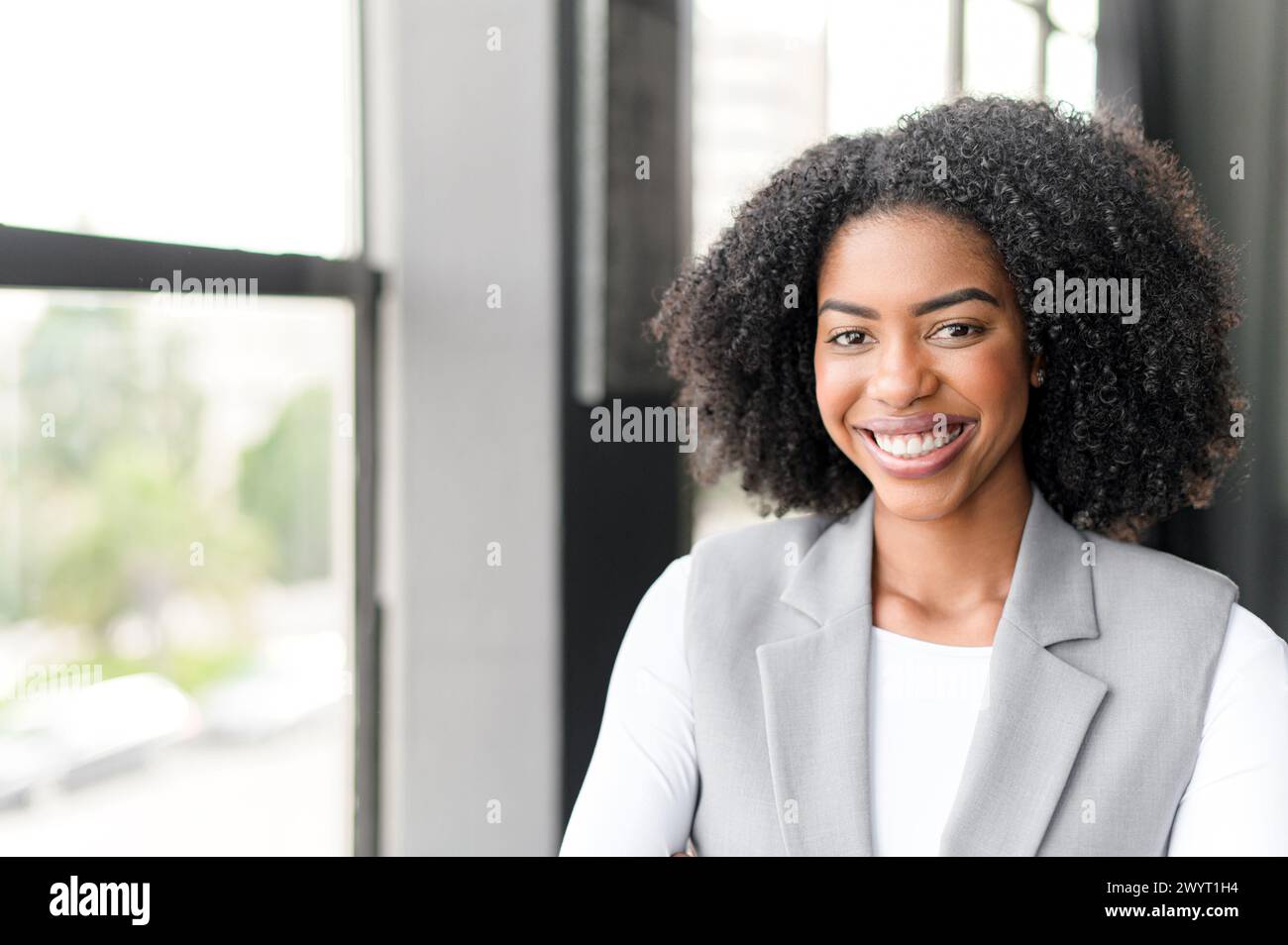 A radiant African-American businesswoman smiles warmly in an office ...