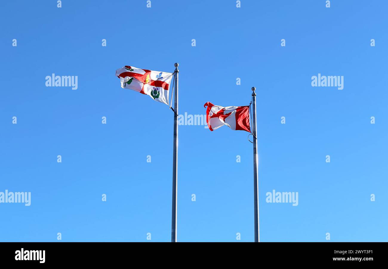 Canadian and Montreal flags waving against blue sky Stock Photo - Alamy