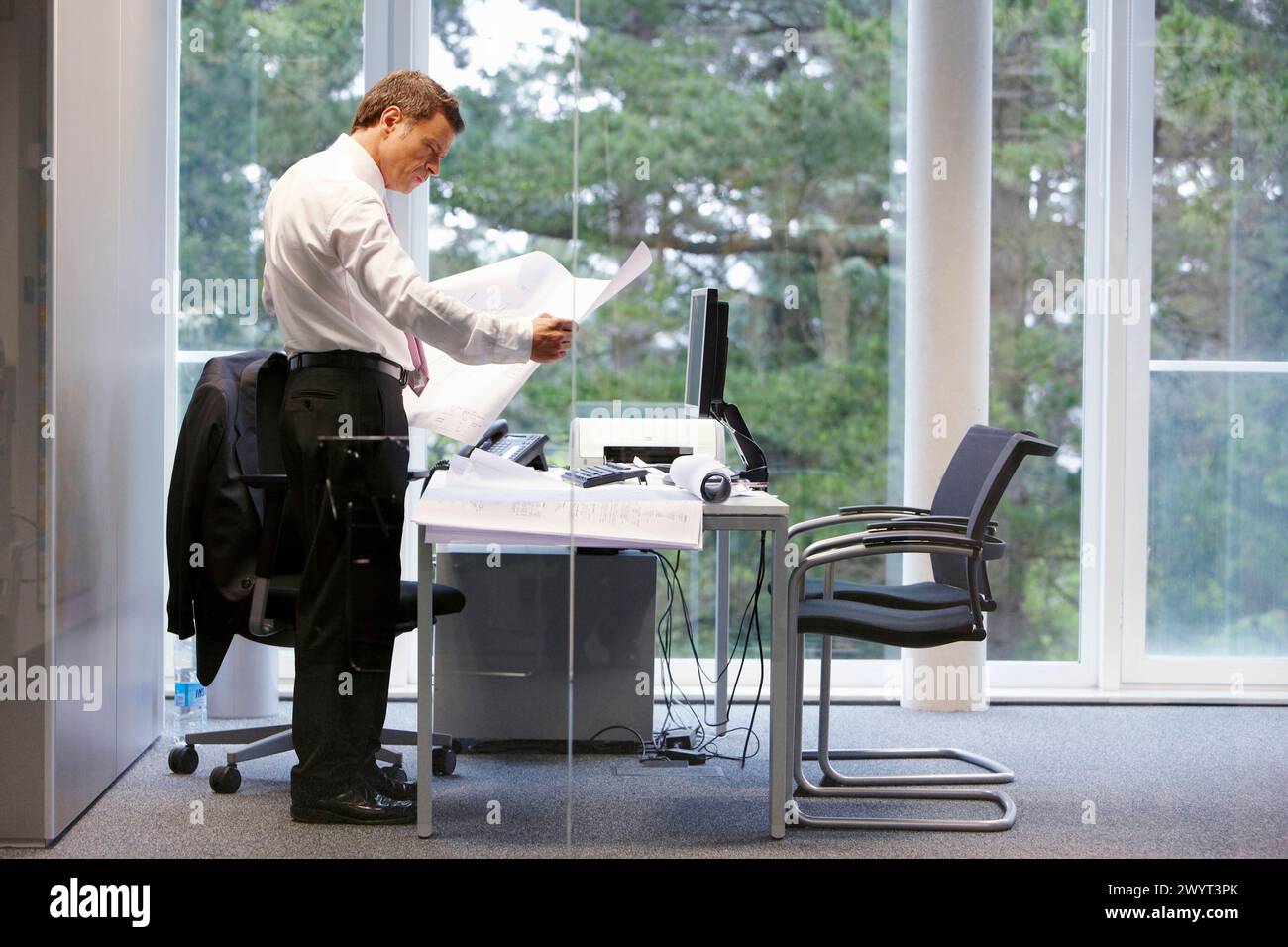 Architect with blueprints in office Stock Photo - Alamy