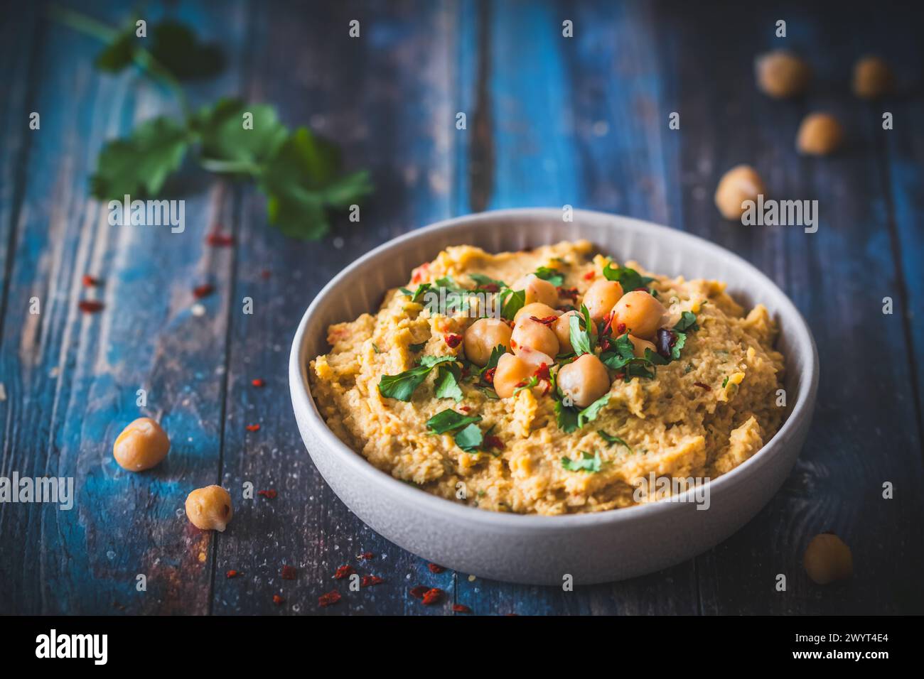 Hummus, chickpea puree with coriander in a bowl on light background ...