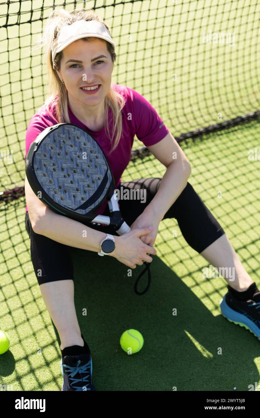 Sporty european woman padel tennis player trains on the outdoor court ...