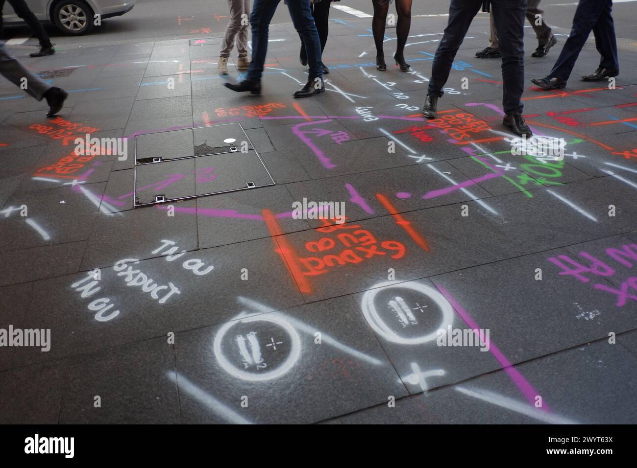 Multi-coloured utility markings painted on a slate coloured pavement ...