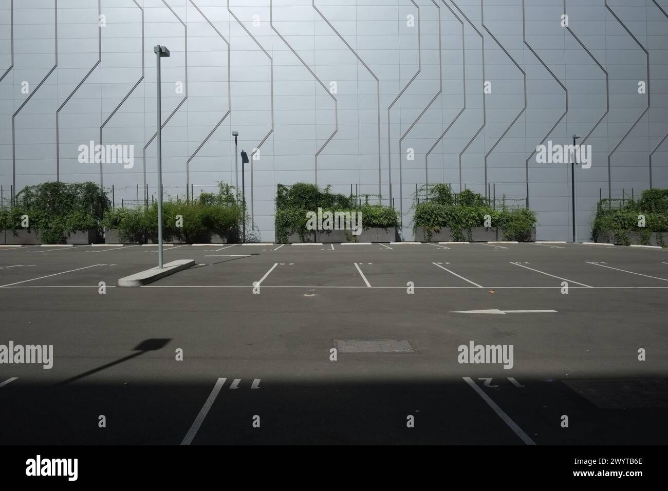 Empty carpark with a silver metallic wall with asymmetric lines ...