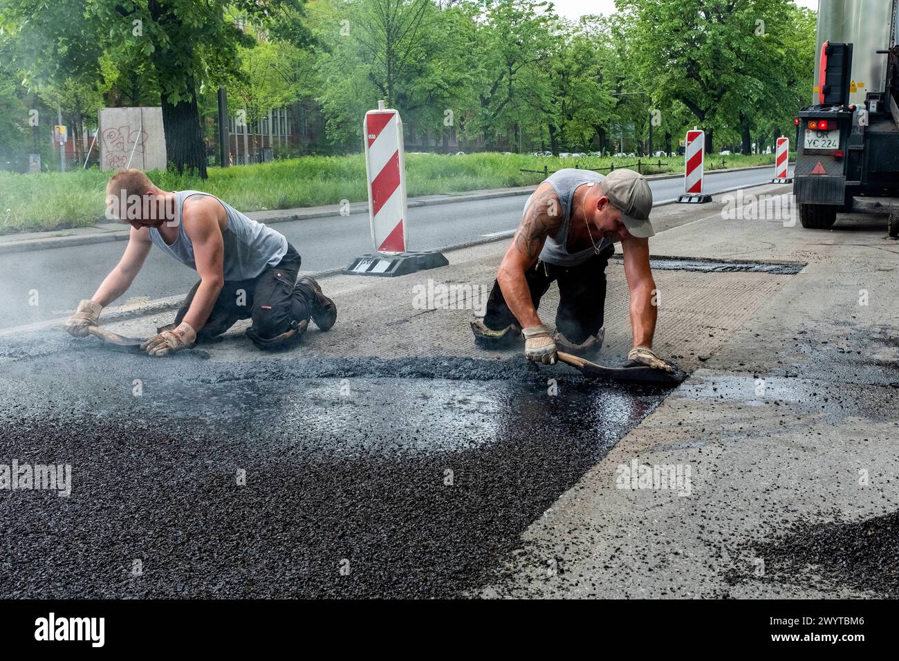 Hard Work on the Road Male Road Workers hard at work to patch a piece ...