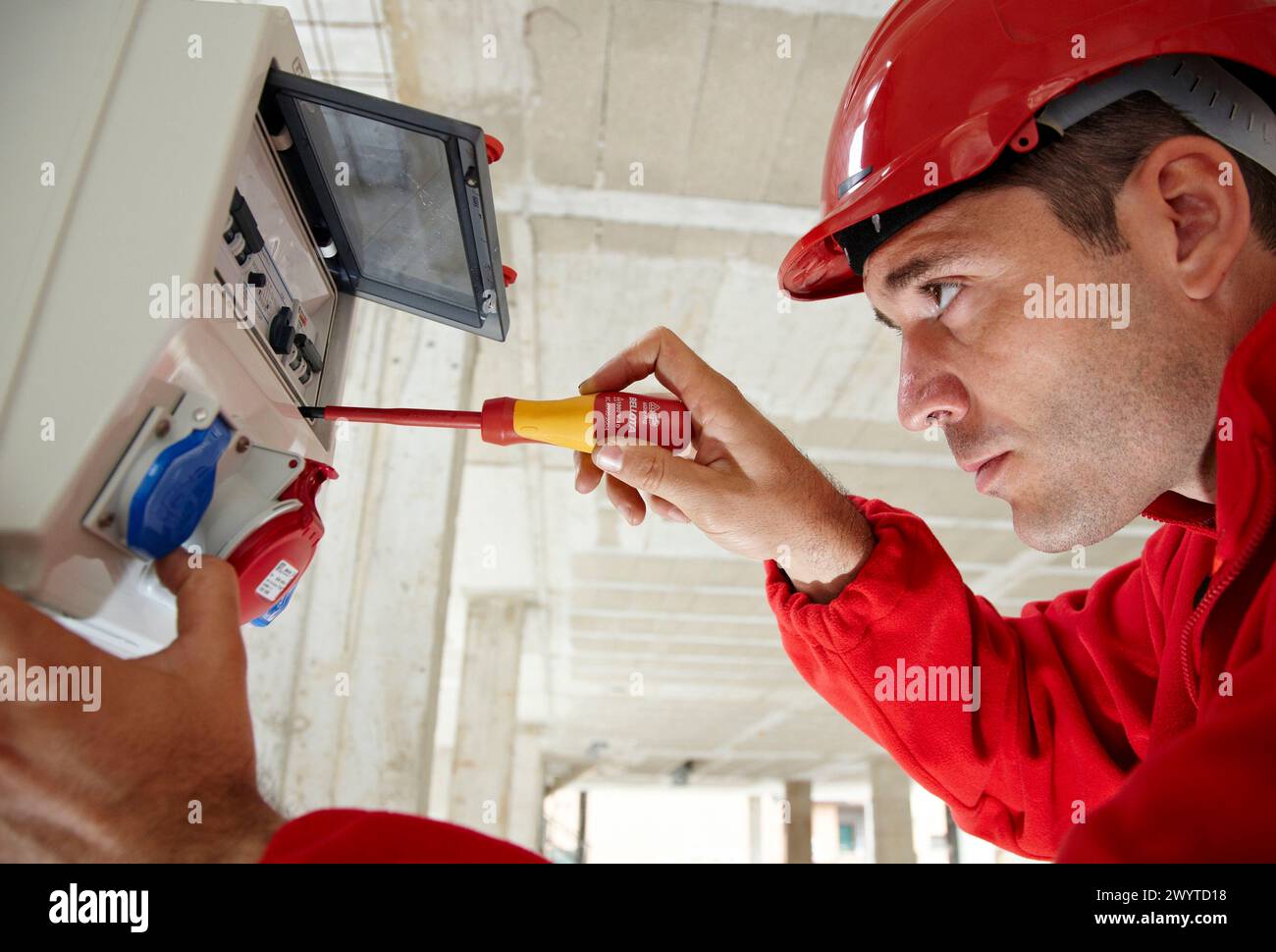 Worker using screwdriver in construction site, fuse box Stock Photo - Alamy