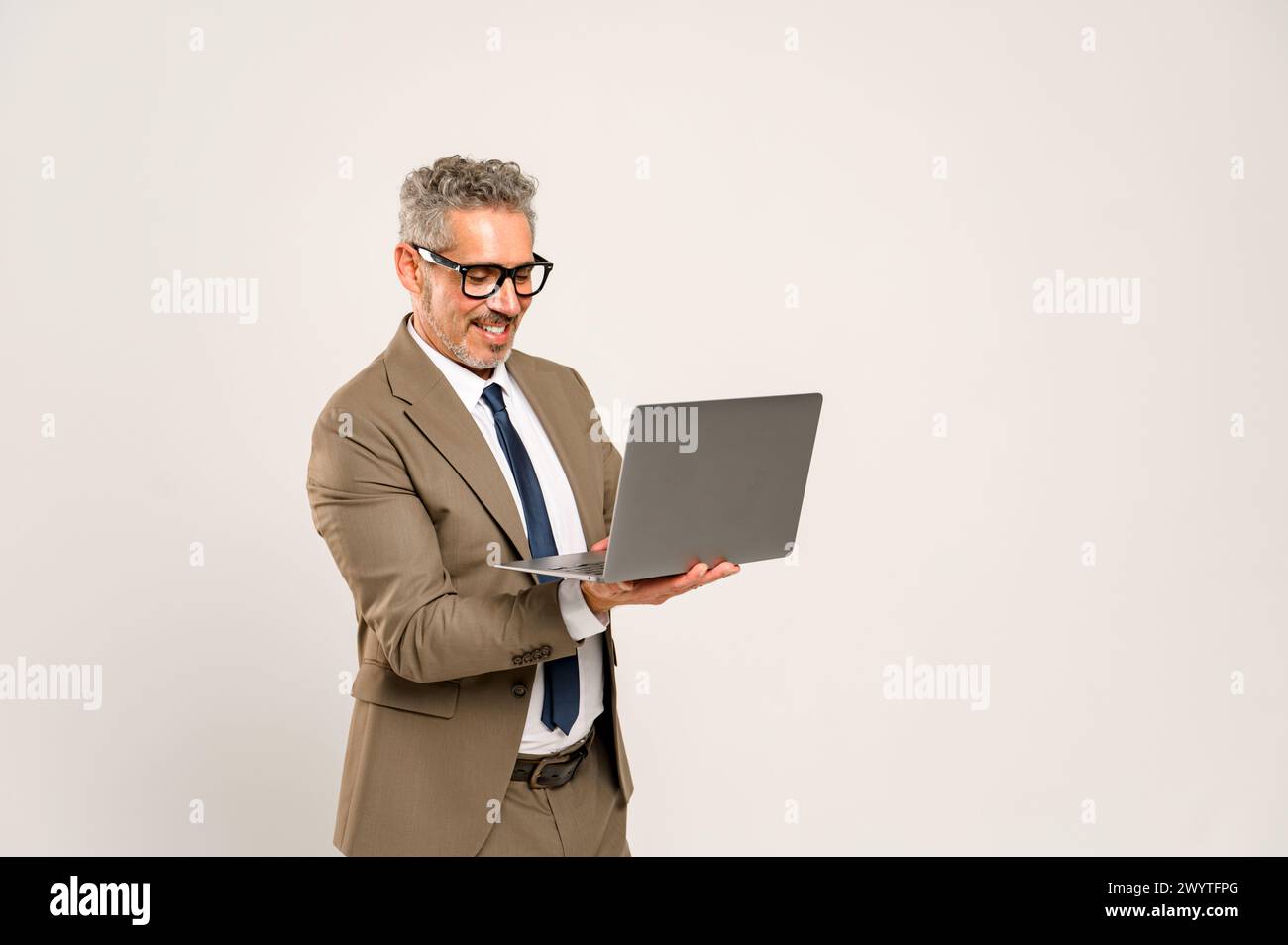 Experienced businessman beams at laptop screen, his formal suit and ...