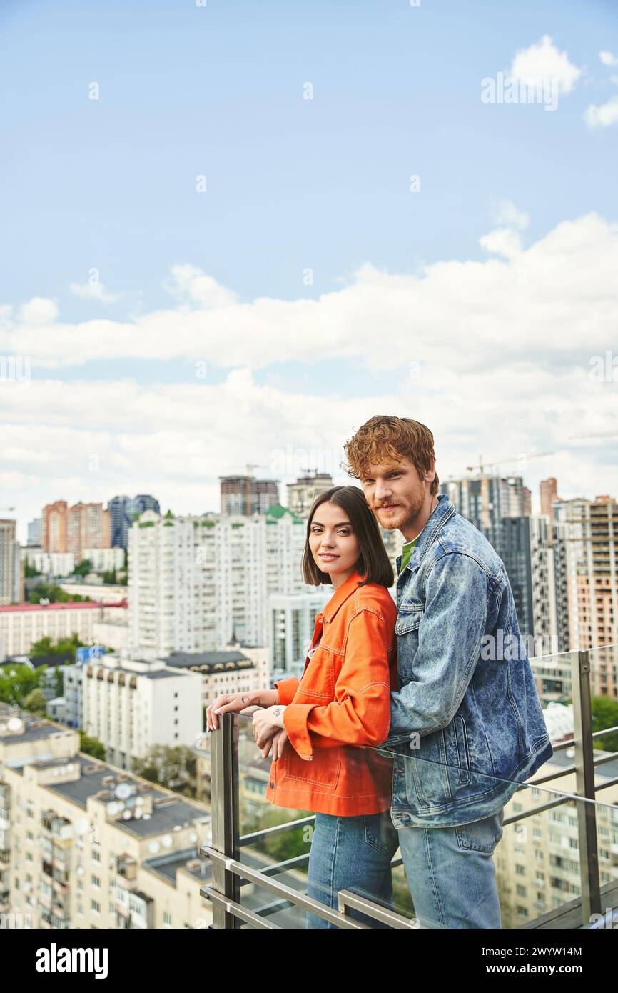 A man and woman embrace while standing on the edge of a tall building ...