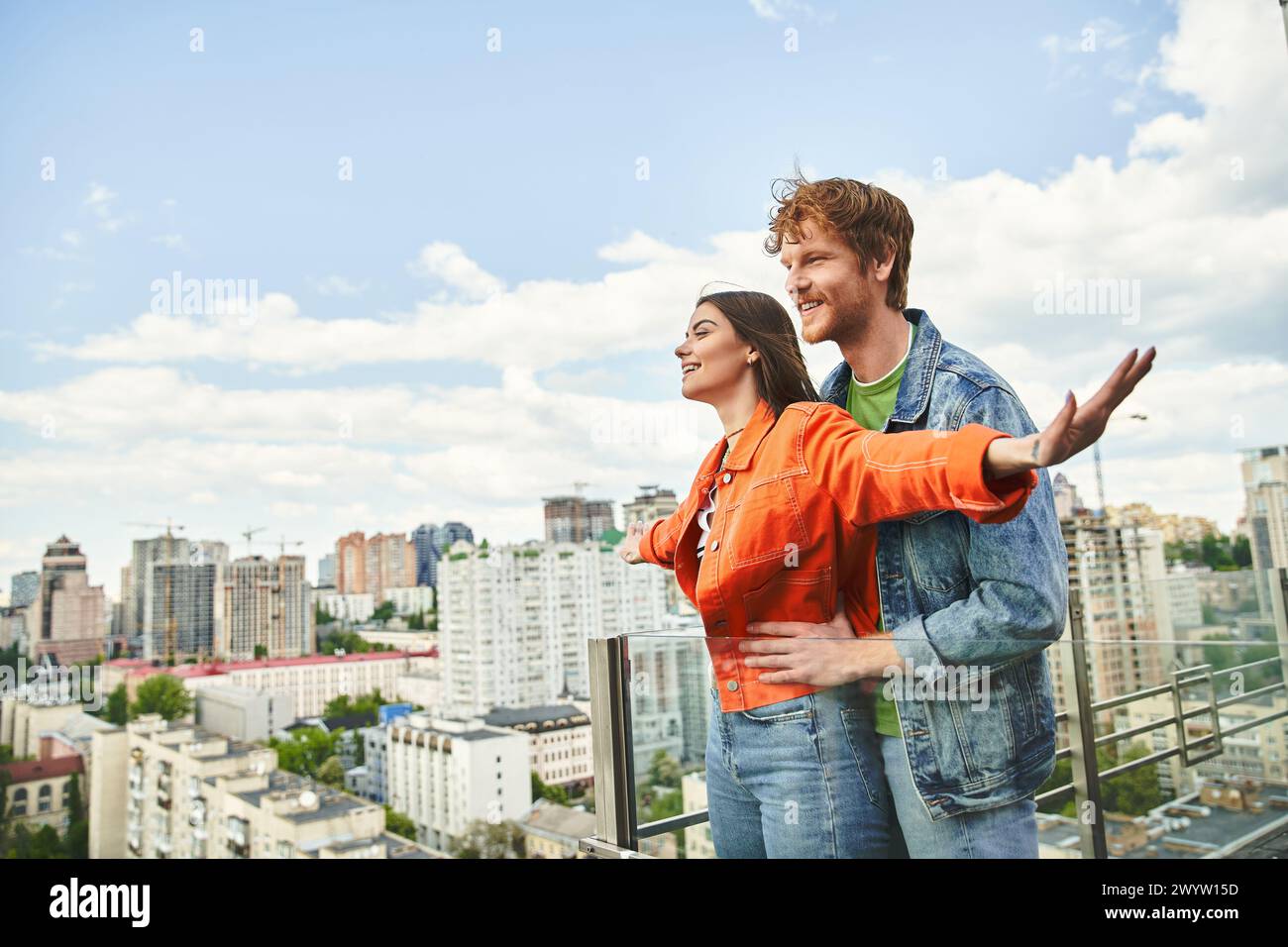 A man and a woman stand confidently on top of a towering building ...