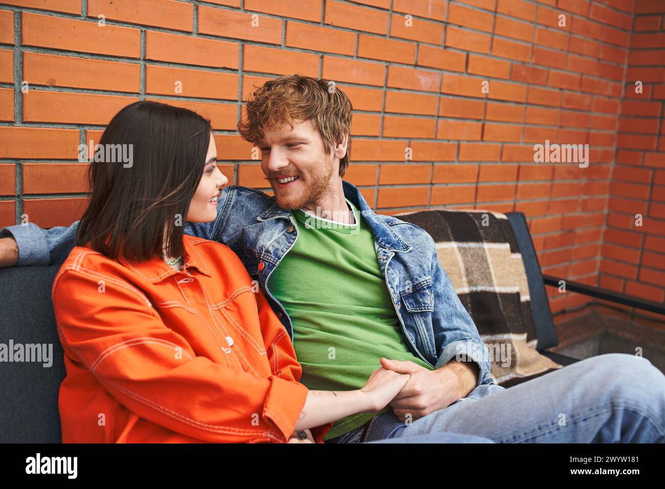 A man and a woman sit comfortably on a couch, enjoying a quiet moment ...
