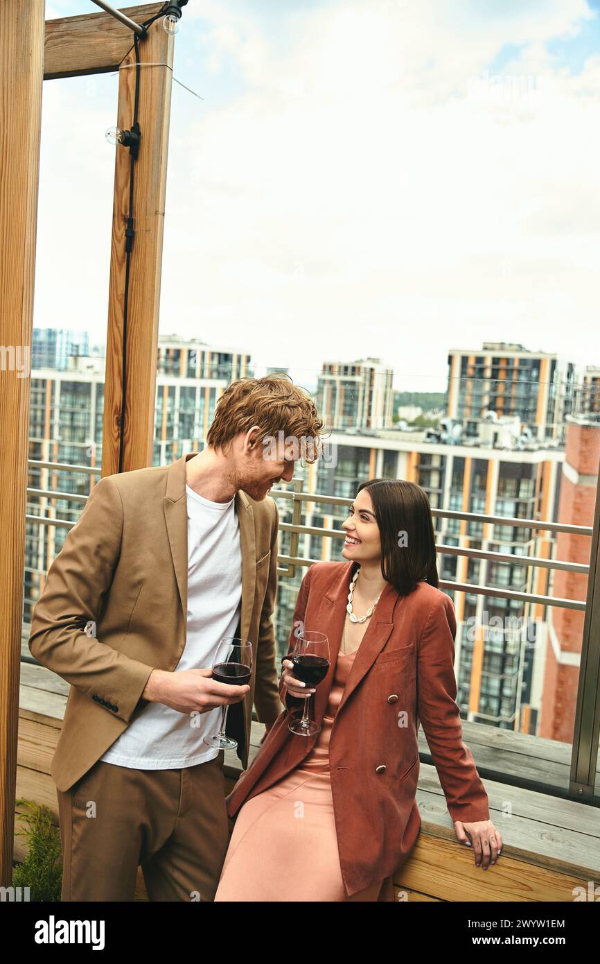 A man in a sharp suit stands next to a woman holding a glass of wine ...