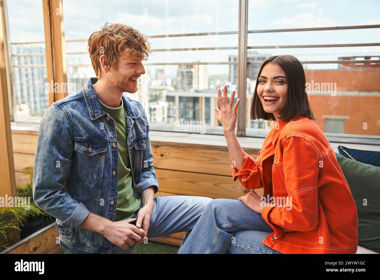 Two friends enjoying a lighthearted conversation on an urban rooftop ...
