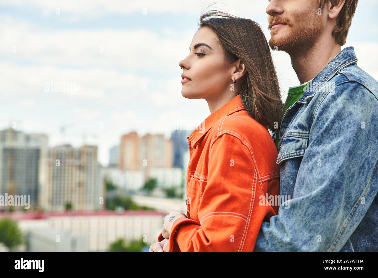 A man and a woman stand side by side, their bodies turned towards each ...