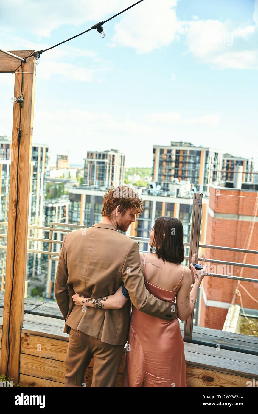 A man and a woman stand confidently on a rooftop, gazing out at the ...