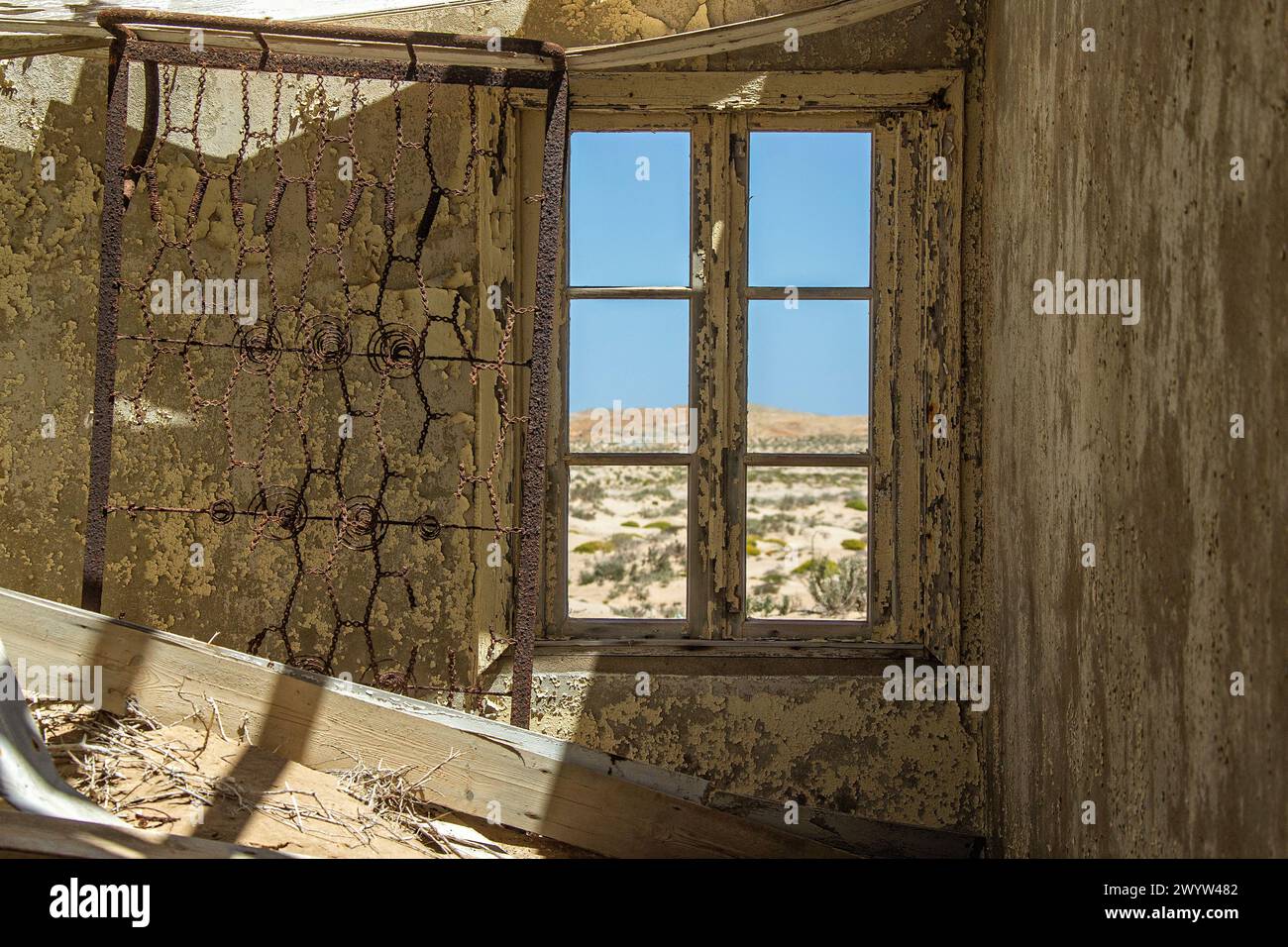 An old, rusty bed frame standing upright by the window of diamond miner ...