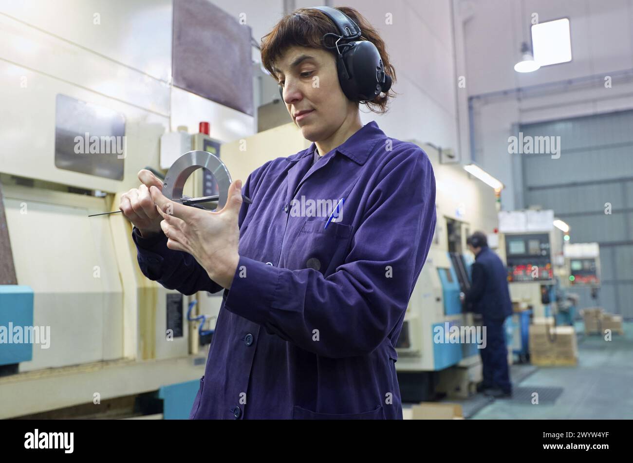 Worker measuring with caliper. Area automated CNC lathes. Machined ...