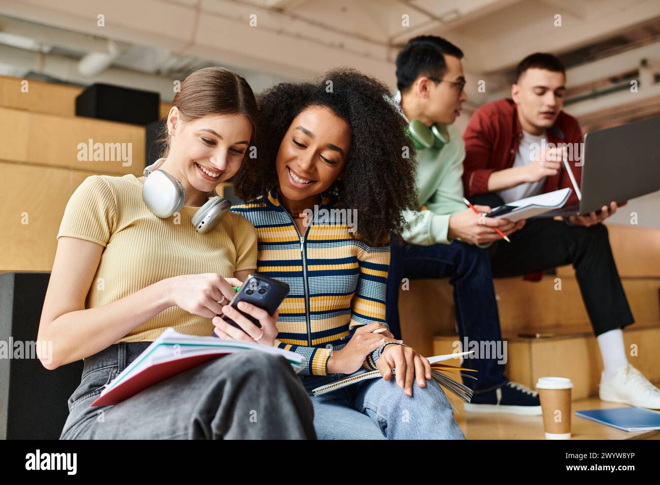 Multicultural students sitting together, engrossed in content on a cell ...