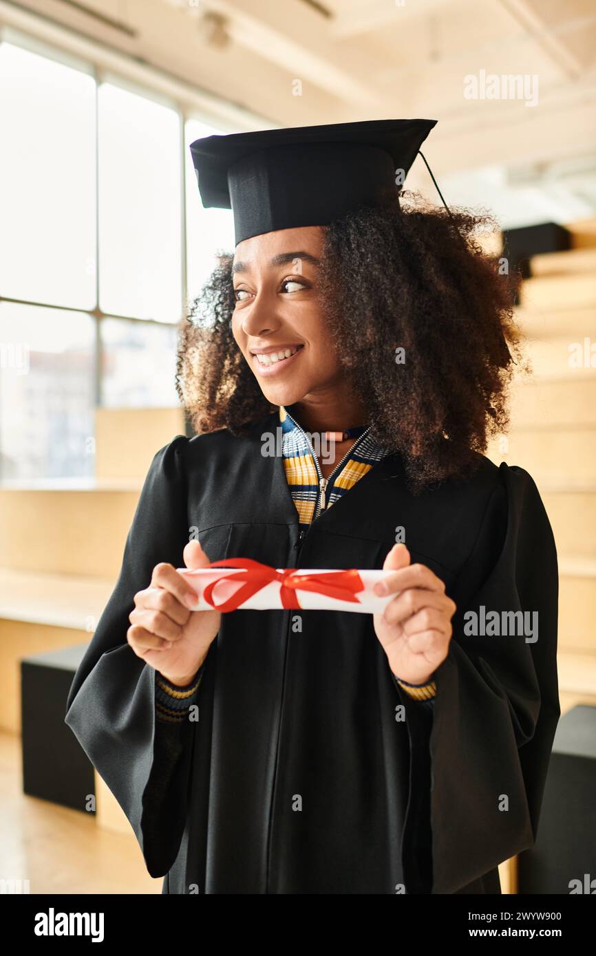 An African American woman in a graduation cap and gown, celebrating her academic achievement ...