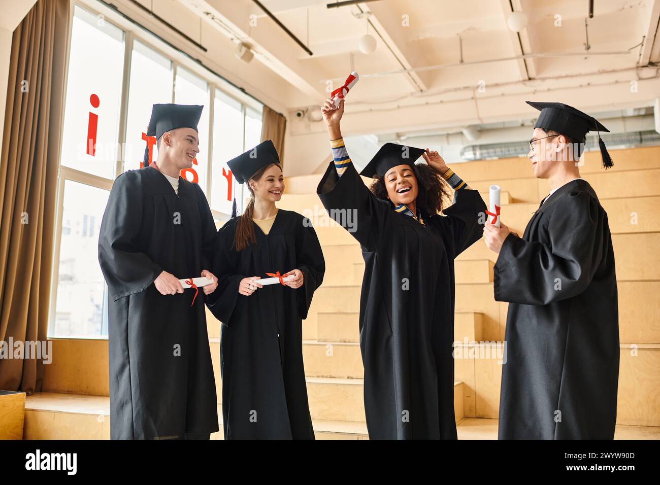 Group of multicultural students in graduation gowns raise their hands ...