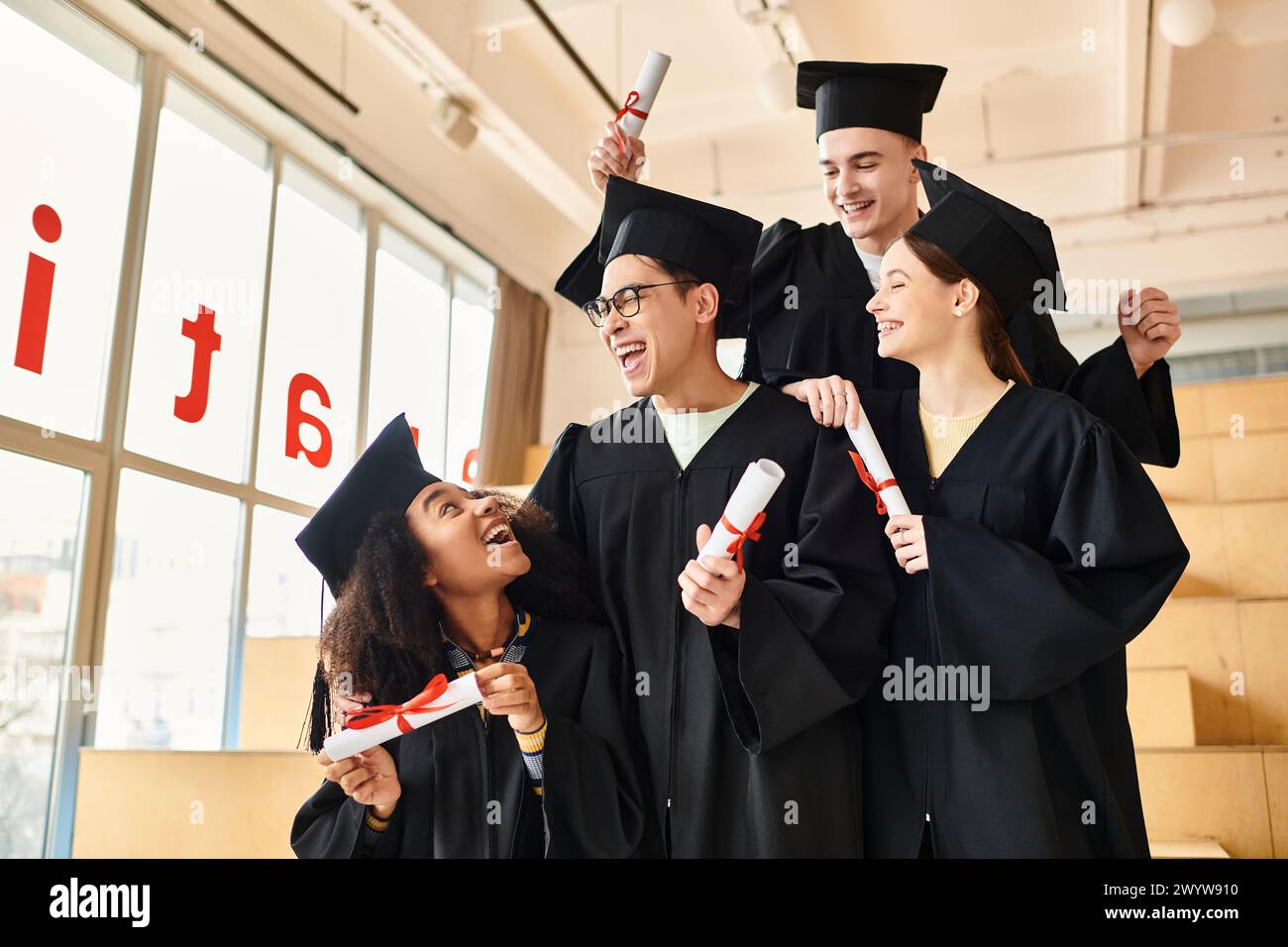 Multicultural group of happy students in graduation gowns holding ...